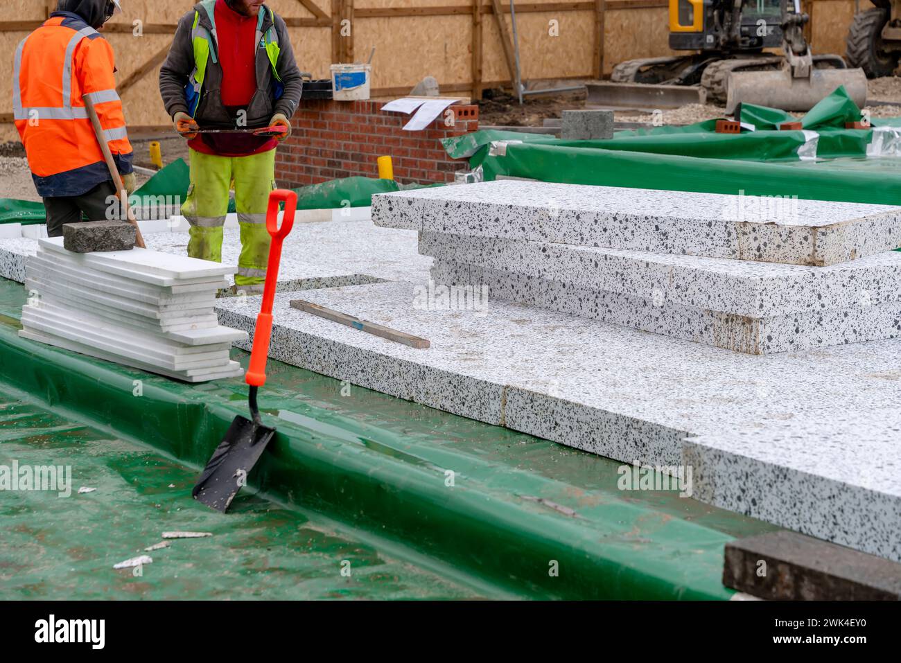 Builder placing polystyrene insulation boards on waterproofing membrane ...