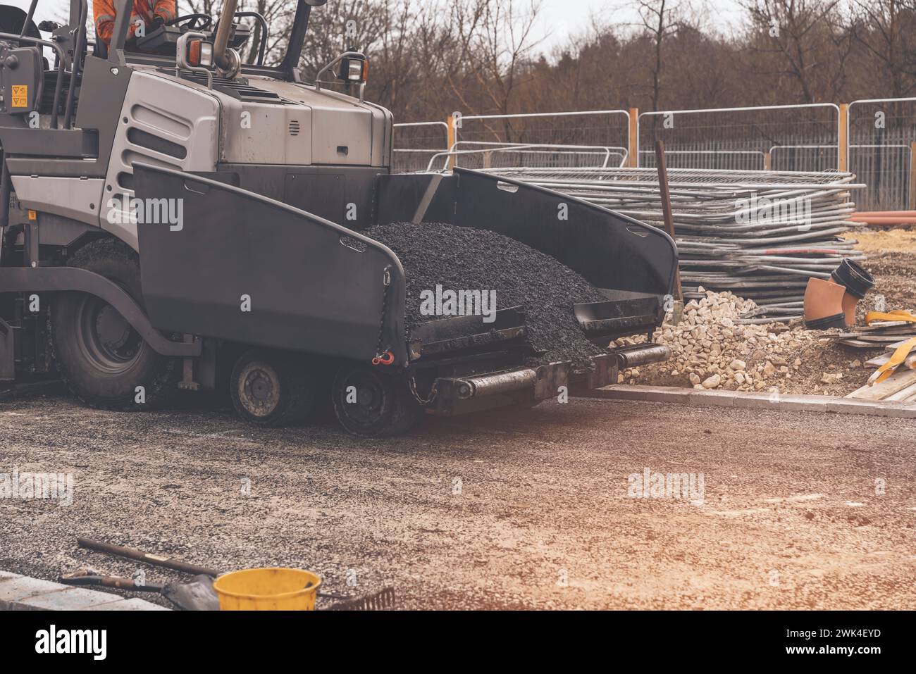 Asphalt paver filled with hot tarmac laying new road surface on new ...
