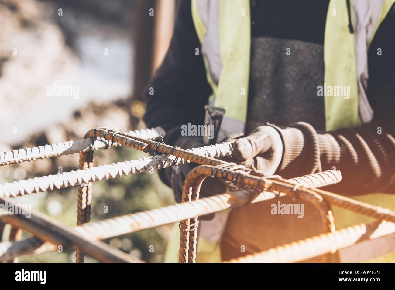 A worker uses steel tying wire to fasten steel rods to reinforcement ...