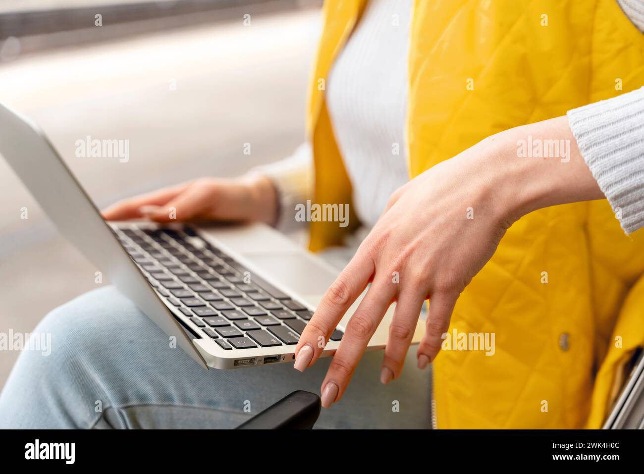 happy woman at the railway station waiting for a train and working on ...
