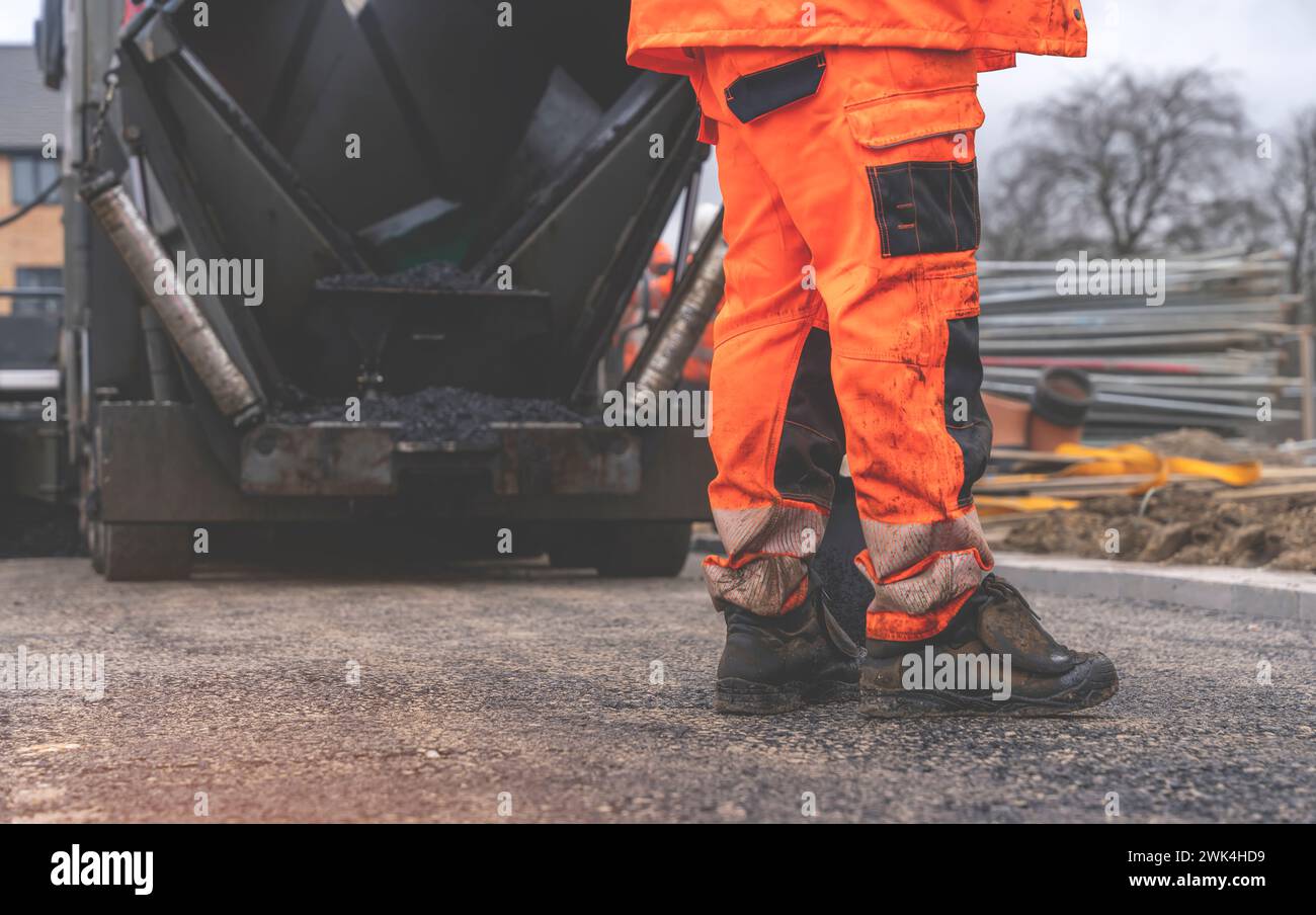 Asphalt paver filled with hot tarmac laying new road surface on new ...