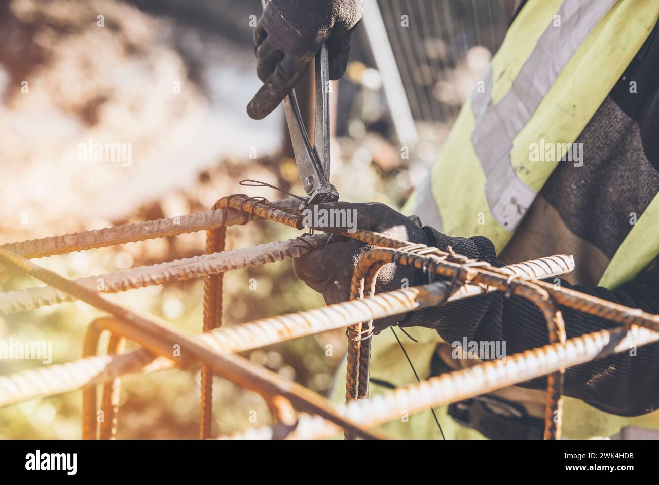 A worker uses steel tying wire to fasten steel rods to reinforcement ...
