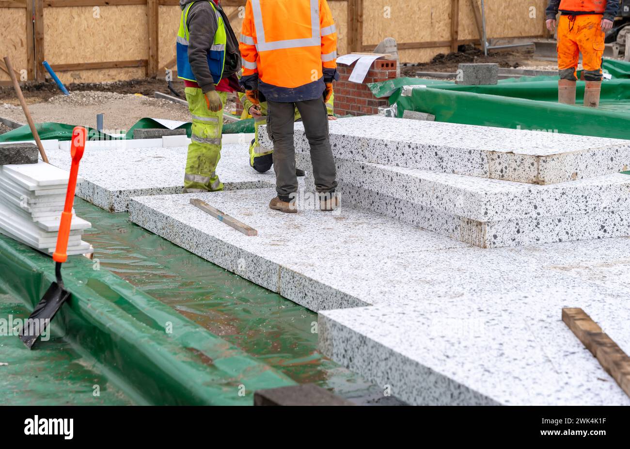 Builder placing polystyrene insulation boards on waterproofing membrane ...