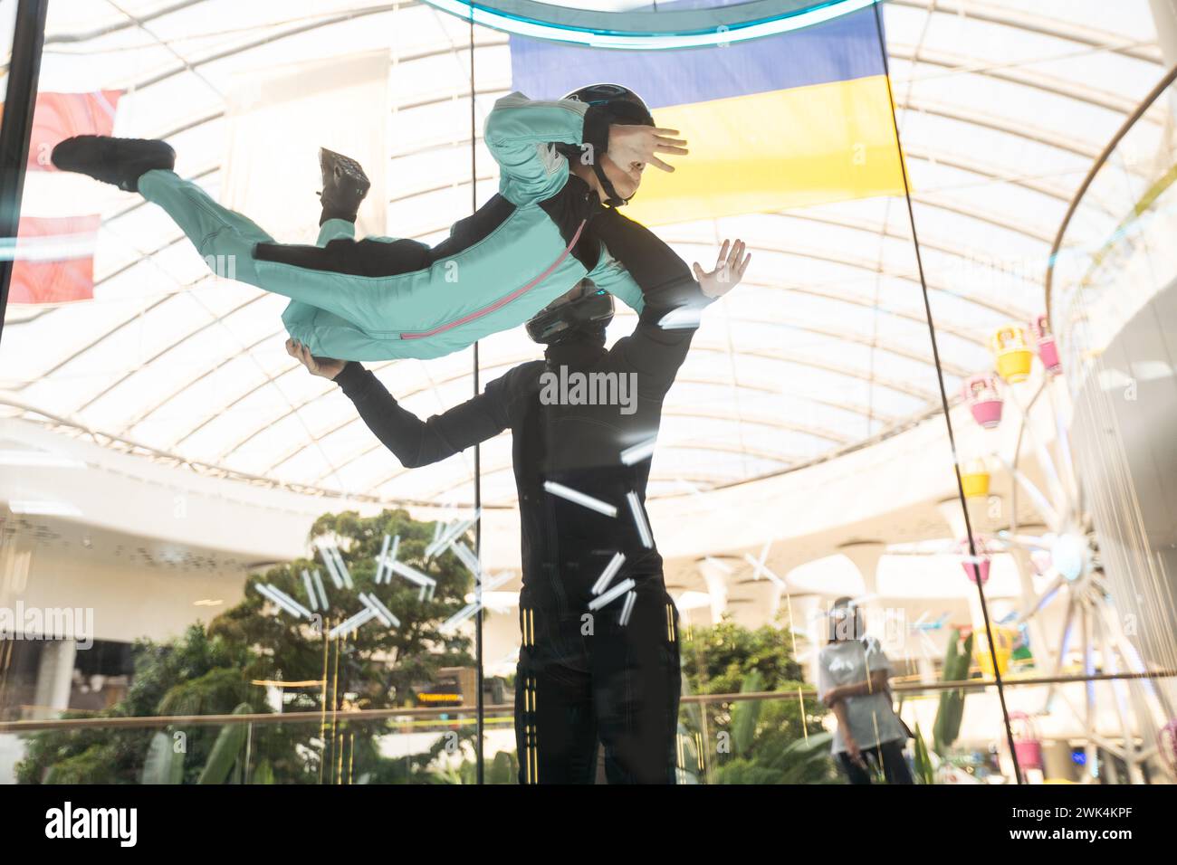 Excited teenage girl in helmet flying in aerodynamic tube wind tunnel ...