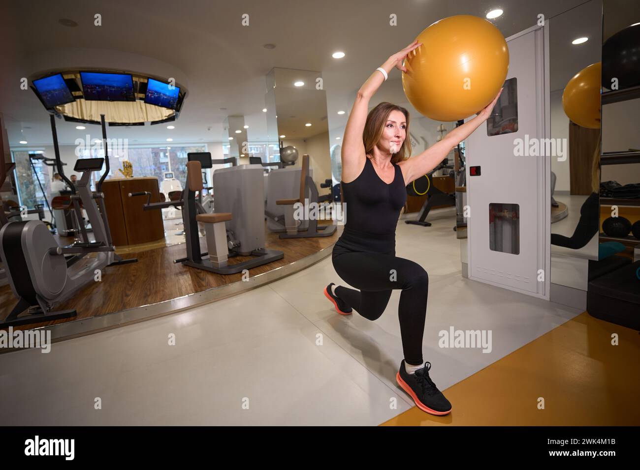 Beautiful woman performs physical exercises in the gym Stock Photo - Alamy