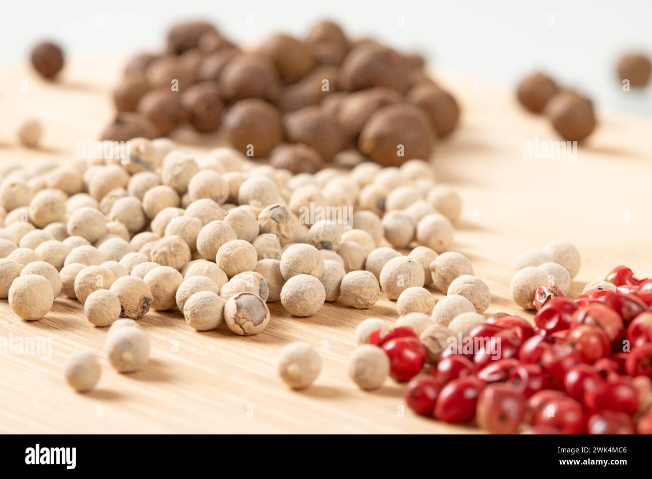 A close-up view of a mix of black, white, and red peppercorns. The ...