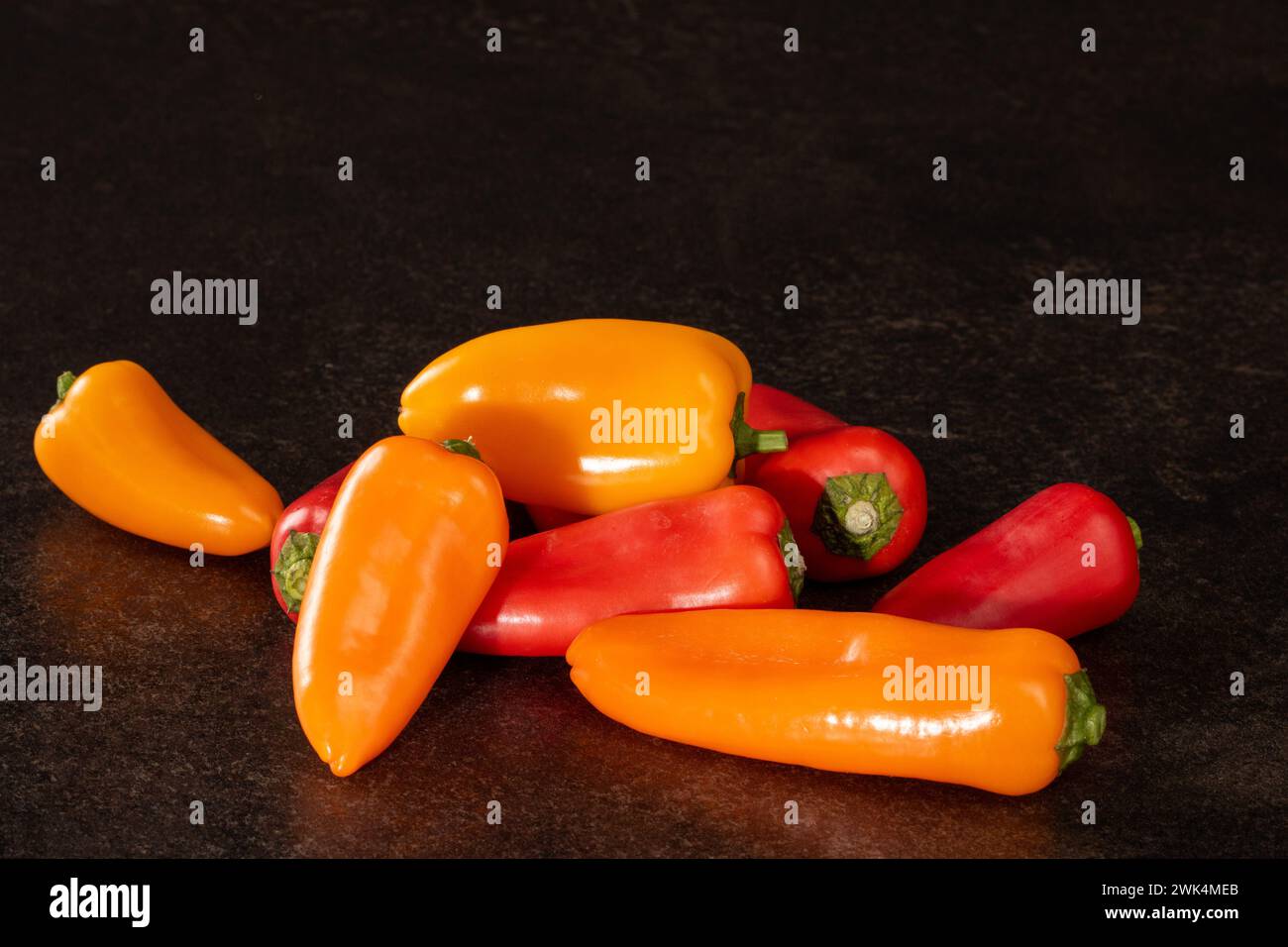 A striking image of a vibrant stack of assorted bell peppers on a dark ...