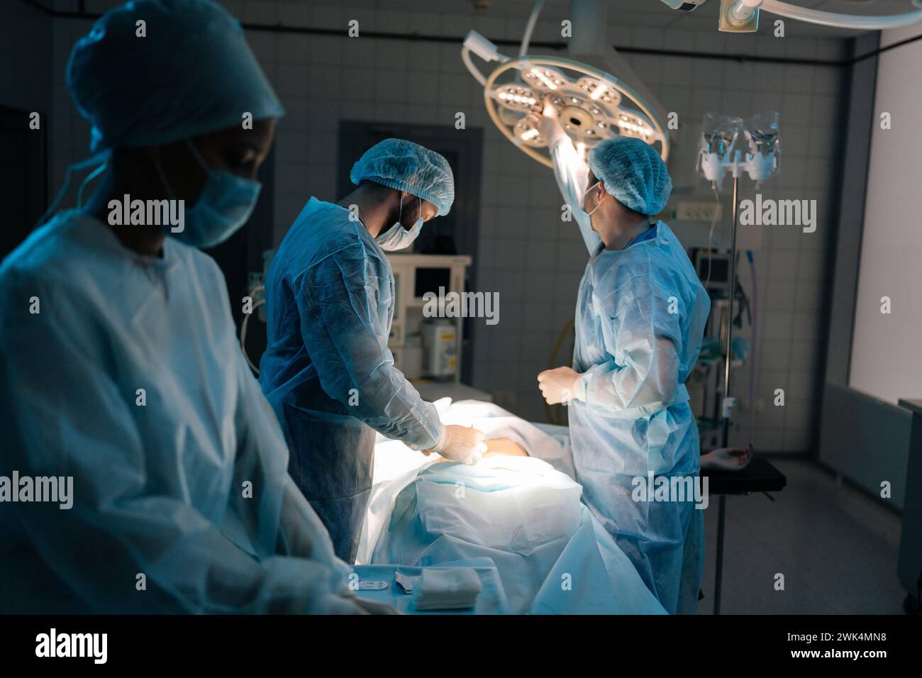 Surgeon in sterile gloves, surgical uniforms and masks adjusting light ...