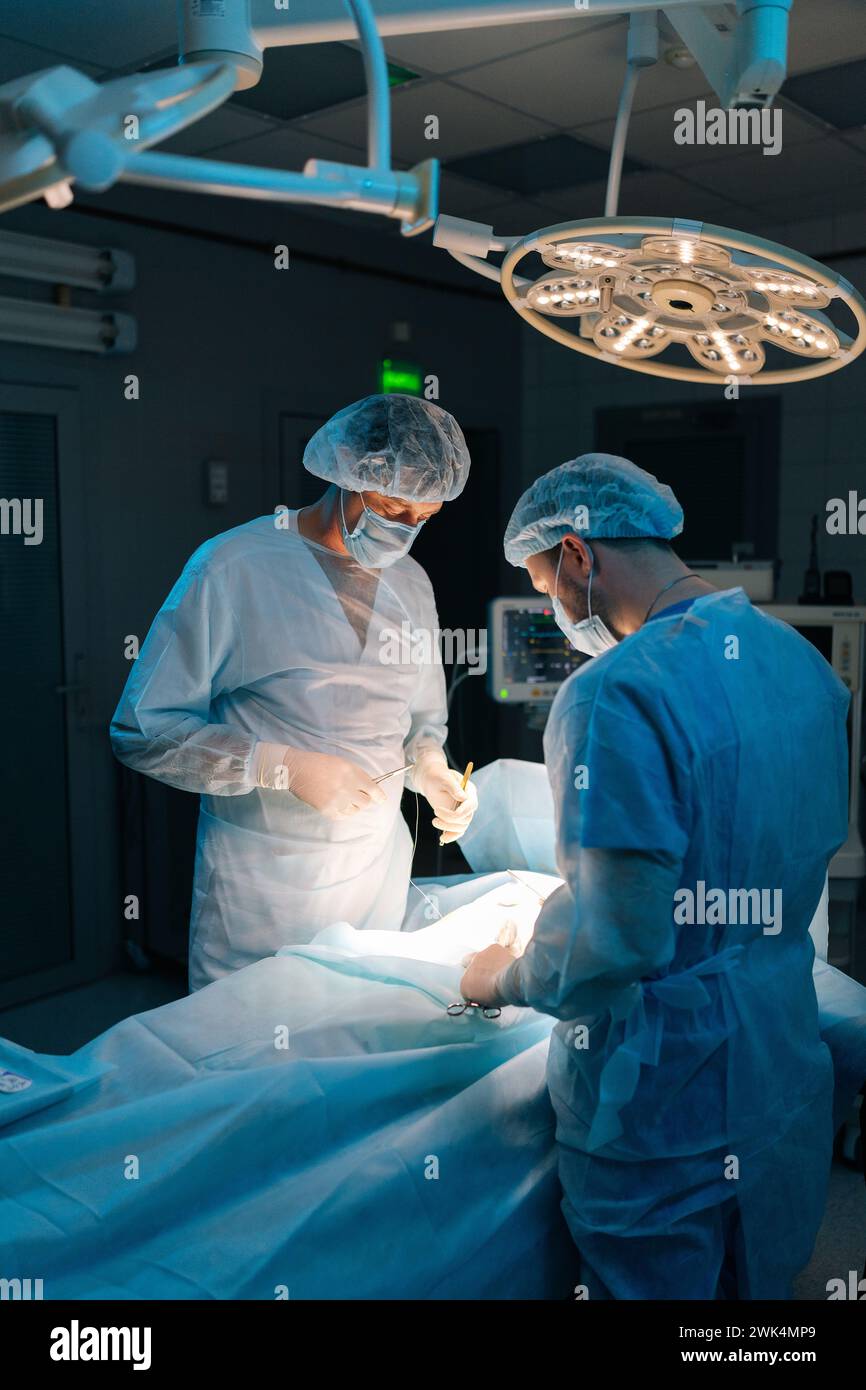 Vertical shot of team of professional surgeons performing invasive ...