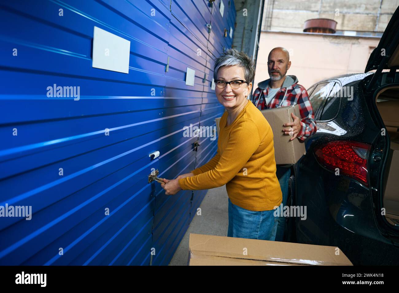 Smiling lady opening storage door for things Stock Photo - Alamy