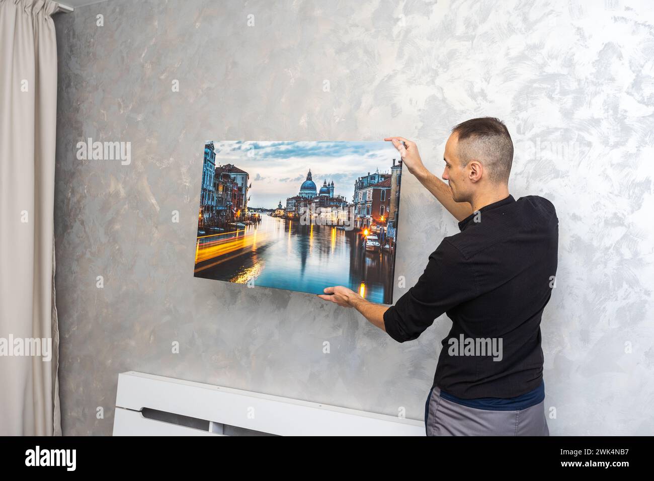 Good-looking adult artist in his 30s is about to hang a colorful little ...