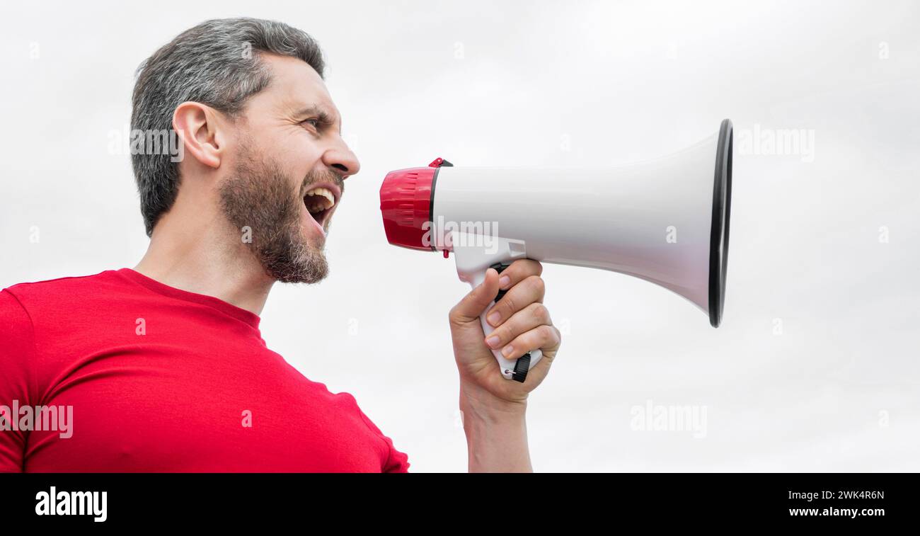 man in red shirt shout in loudspeaker on sky background. propaganda ...
