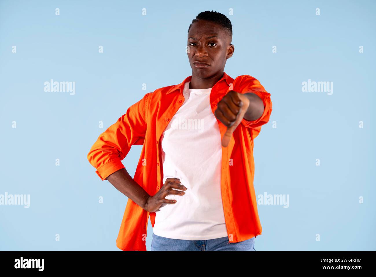 woman in orange shirt giving thumb down gesture, dislikes something ...