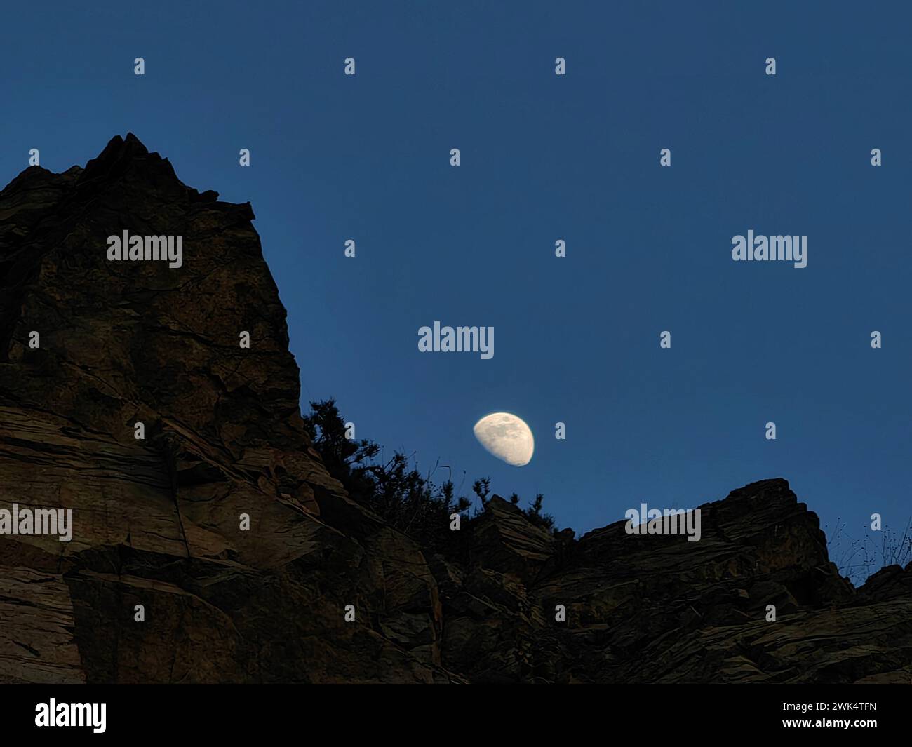 Cliffside glow. Half moon phase above rocky outcrops Stock Photo - Alamy
