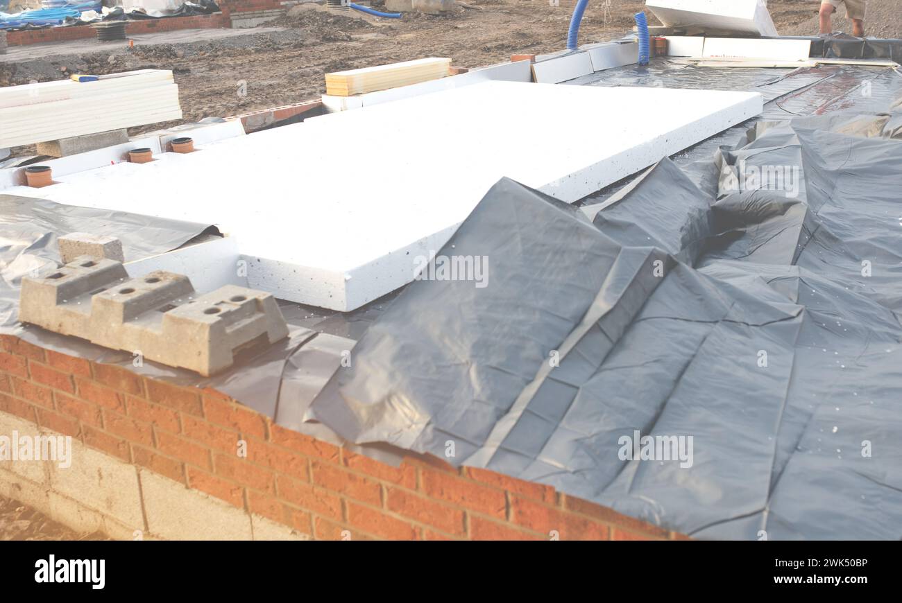 Builder placing polystyrene insulation boards on waterproofing membrane ...