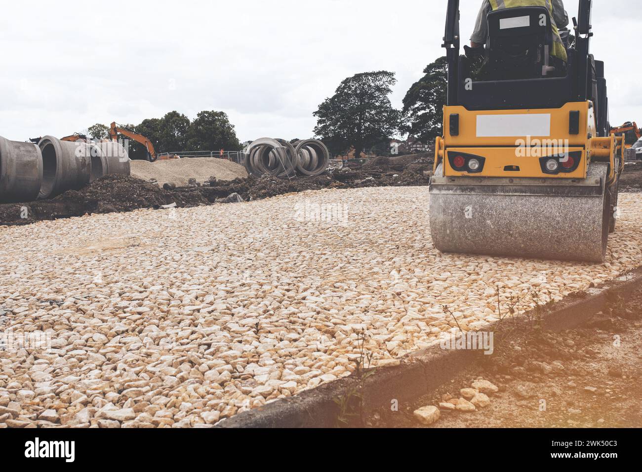 Road roller compacting stone during new road construction in ...