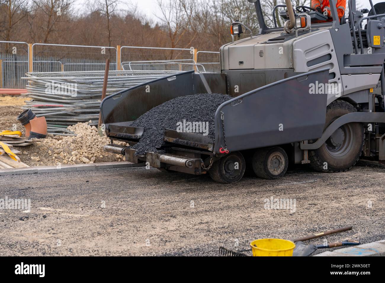 Asphalt paver filled with hot tarmac laying new road surface on new ...