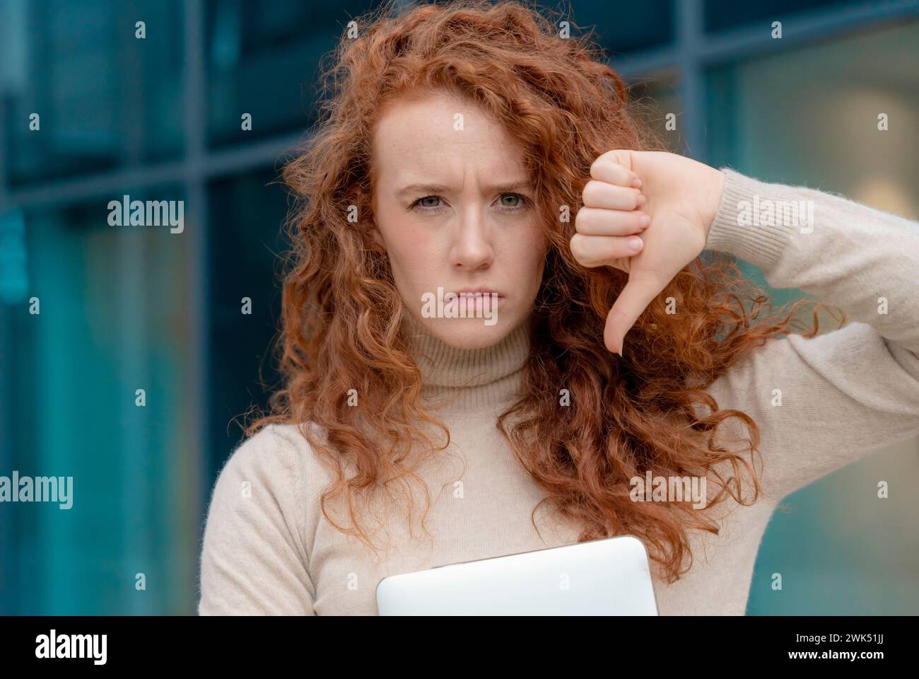 woman in sweater giving thumb down gesture, dislikes something, having ...