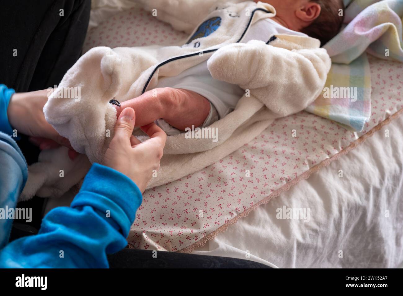 mother changing pampers for her baby , holding his tiny leg while ...