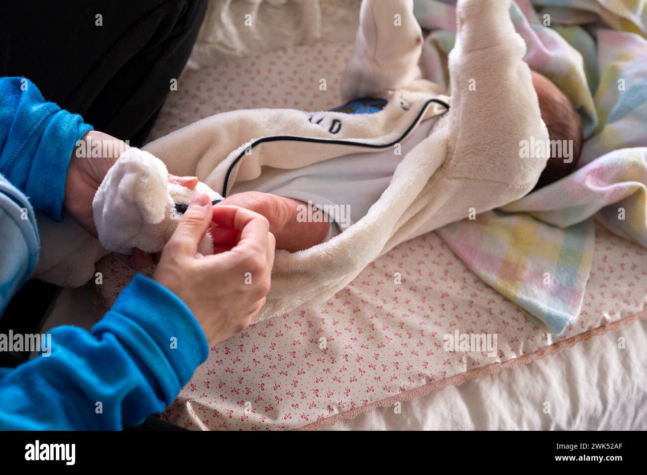 mother changing pampers for her baby , holding his tiny leg while ...