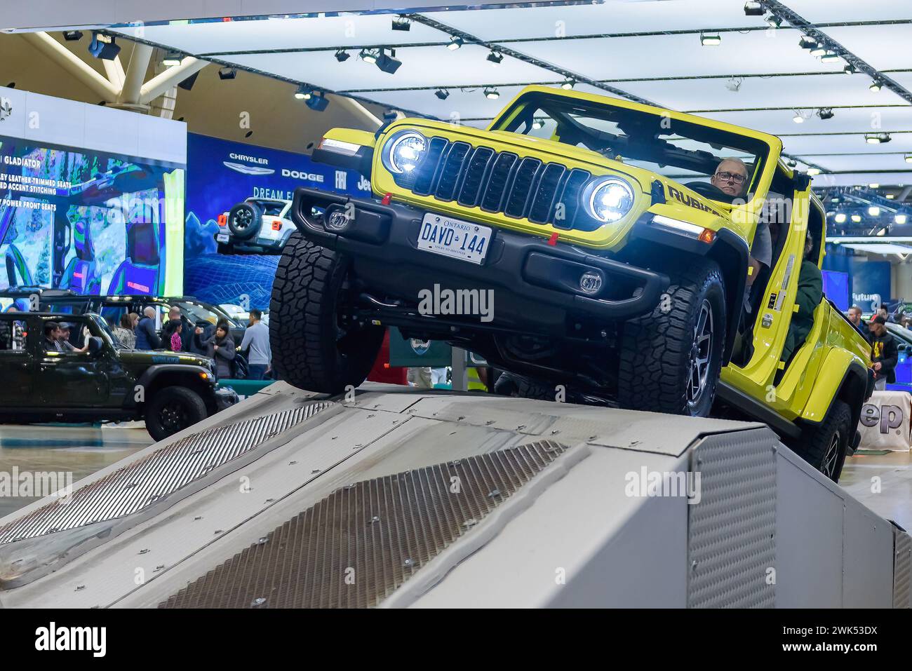 A yellow Jeep Wrangler vehicle driving in a closed course with ...