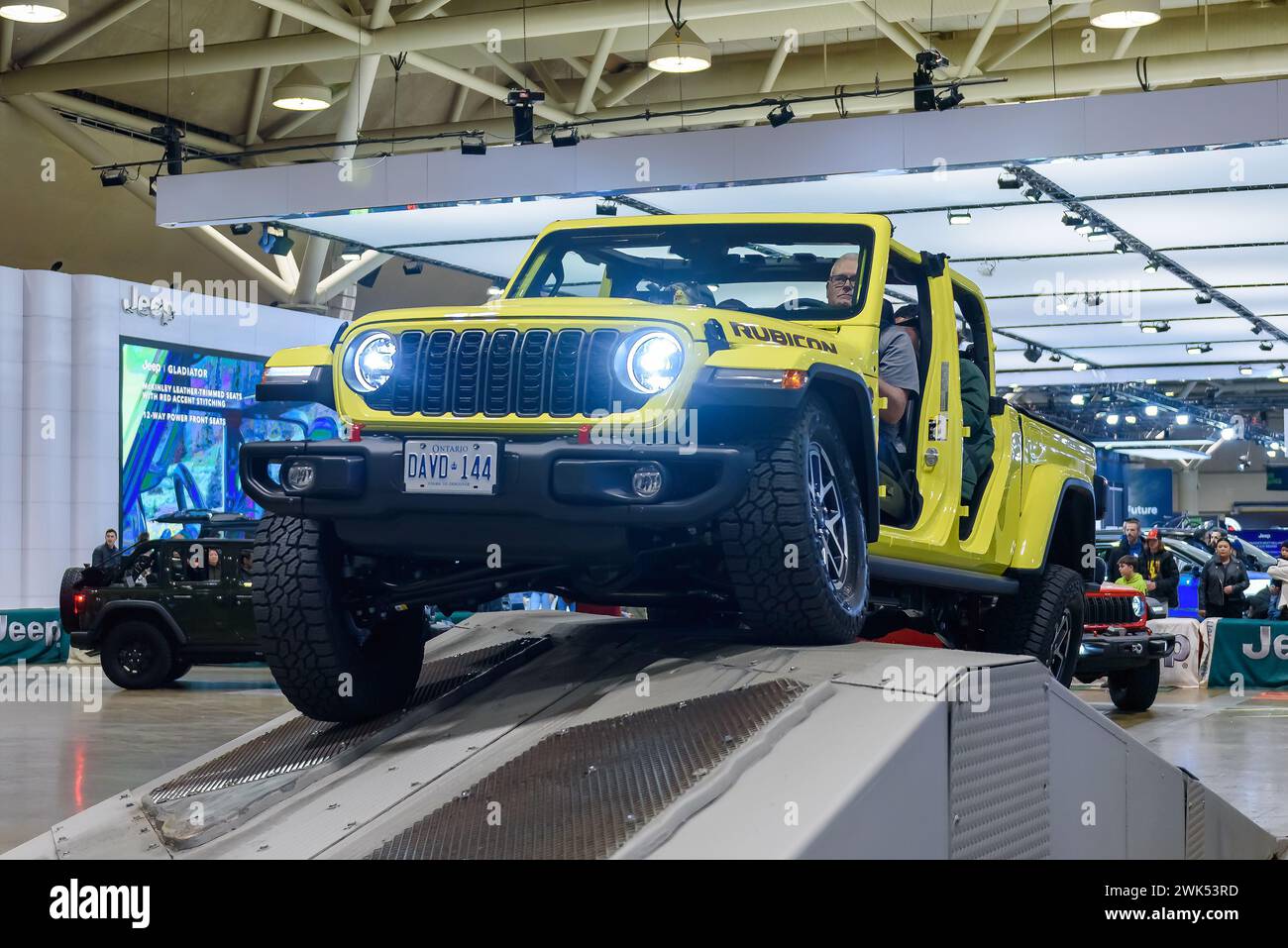 A yellow Jeep Wrangler vehicle driving in a closed course with ...