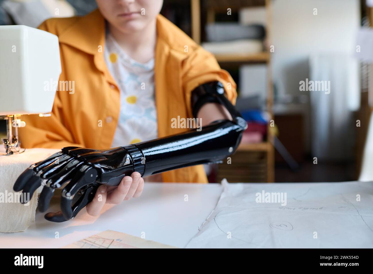 Close up of young woman with disability adjusting prosthetic arm while ...