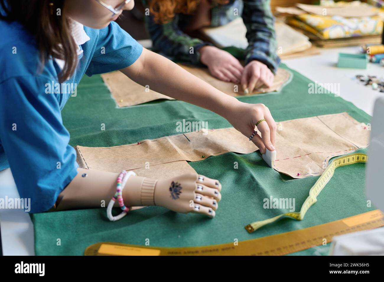 Cropped shot of girl with prosthetic arm making clothing and tracing ...