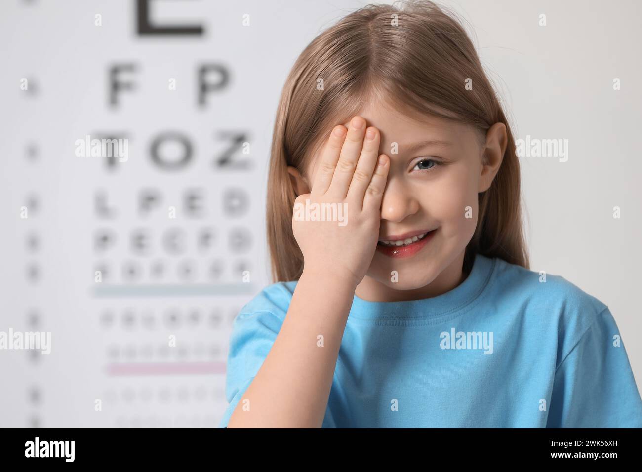 Little girl covering her eye against vision test chart Stock Photo - Alamy