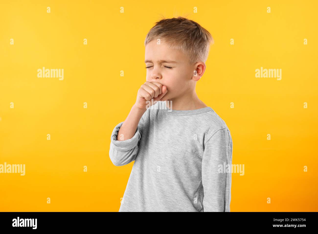 Sick boy coughing on yellow background. Cold symptoms Stock Photo - Alamy