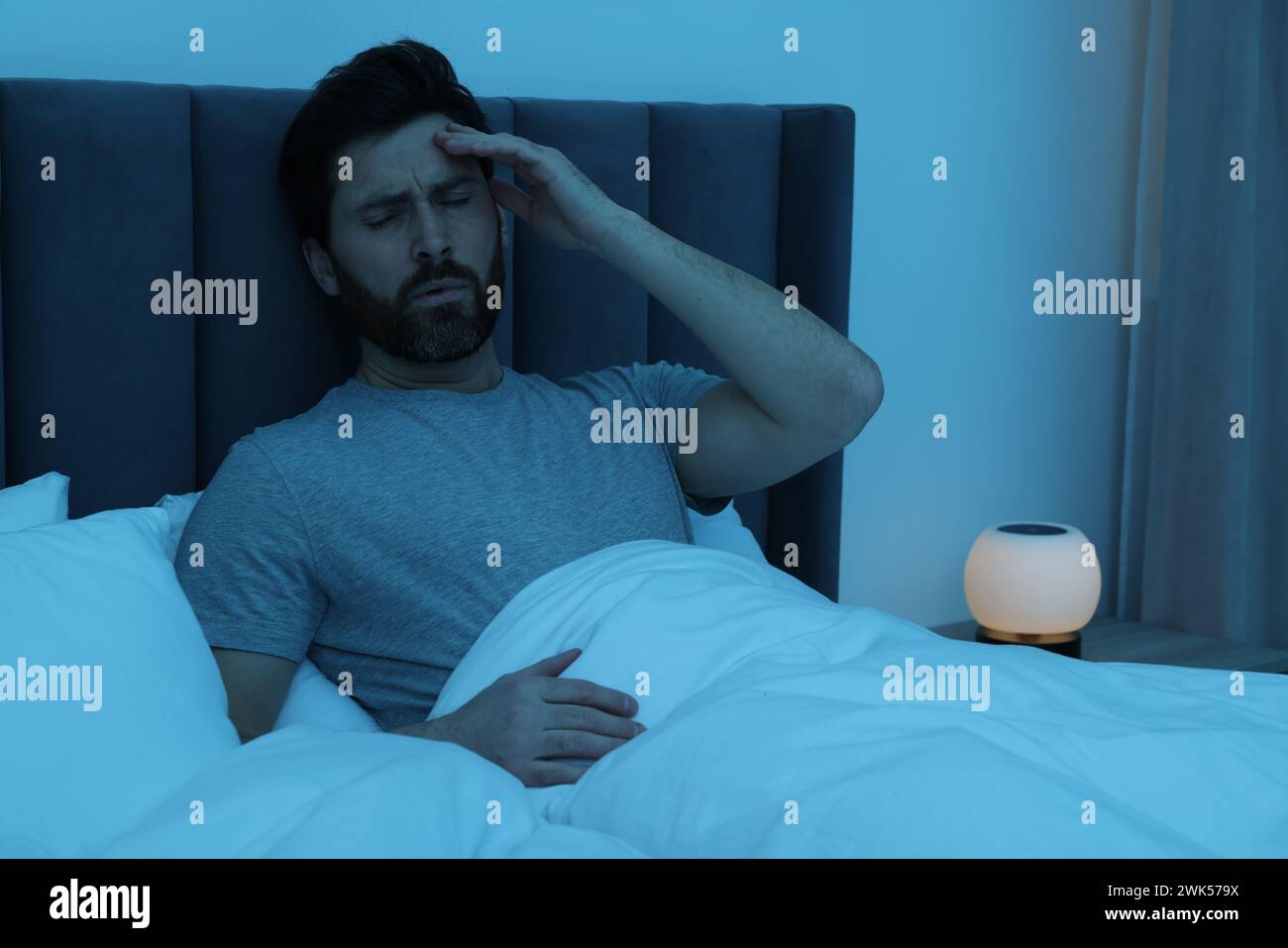 Man suffering from headache in bed at night Stock Photo - Alamy