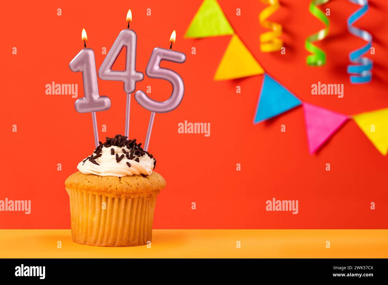 Birthday cupcake with number 145 candle - Sparkling orange background ...