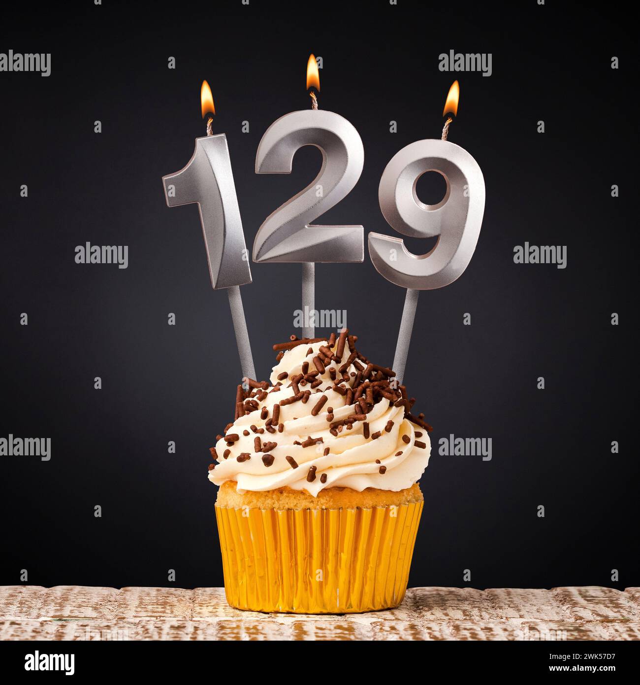 Birthday candle number 129 - Anniversary cupcake on black background ...