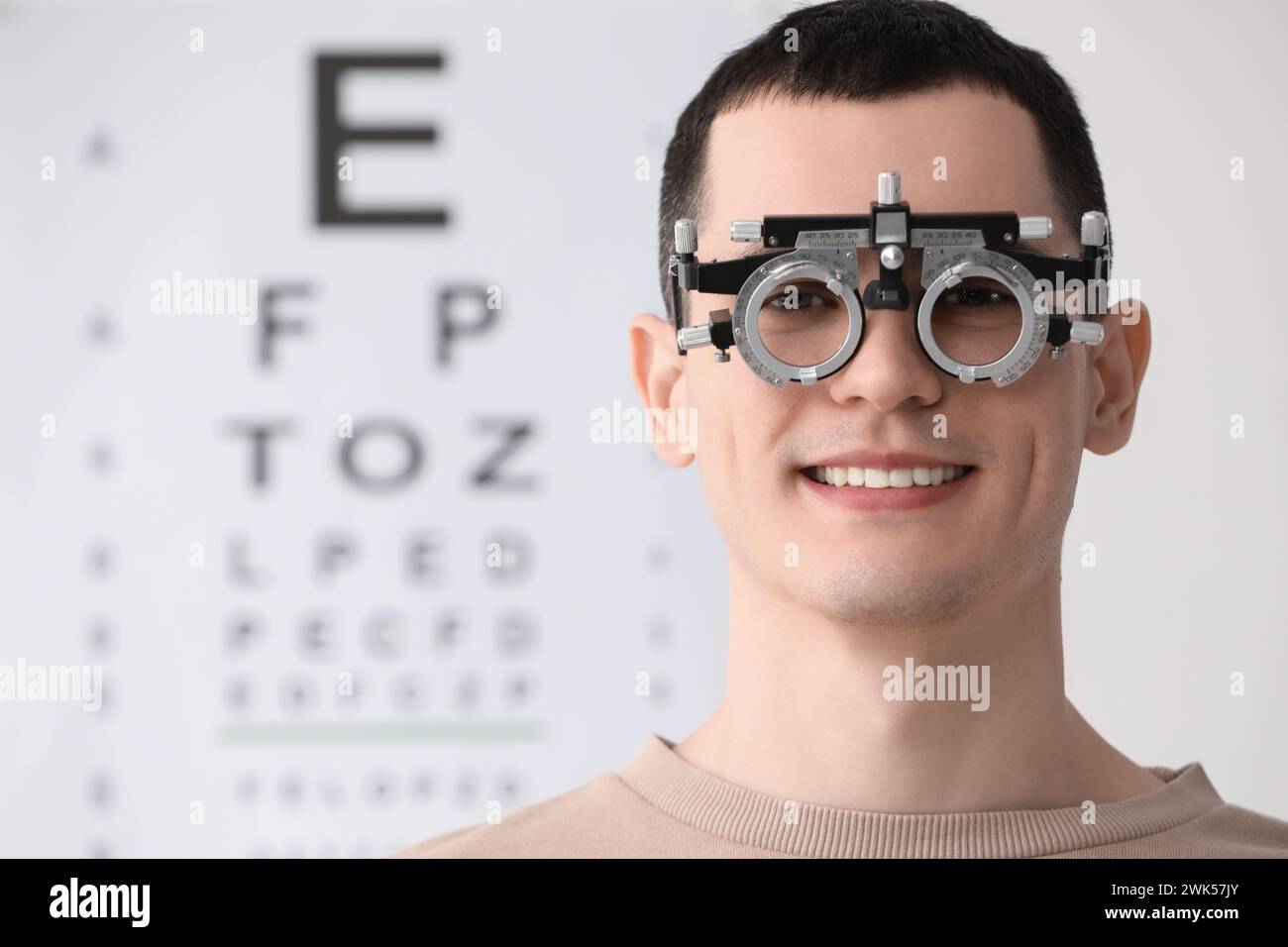 Young man with trial frame against vision test chart Stock Photo - Alamy
