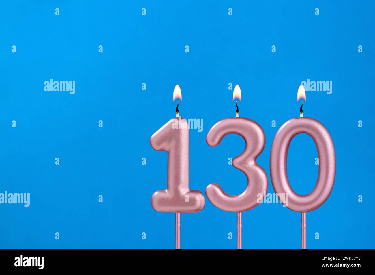 Number 130 - Burning anniversary candle on blue foamy background Stock ...