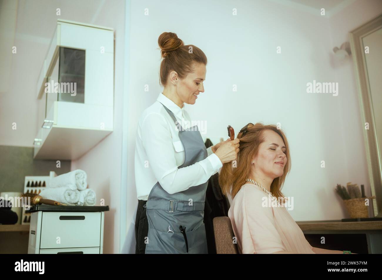 40 years old woman hairdresser in modern beauty salon with hairbrush ...