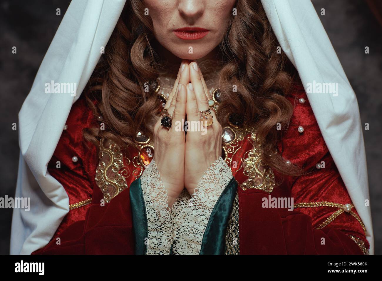 Closeup on medieval queen in red dress with veil praying Stock Photo ...