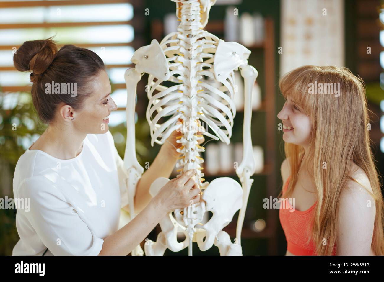 Healthcare time. happy female medical massage therapist in massage cabinet with teenage client ...