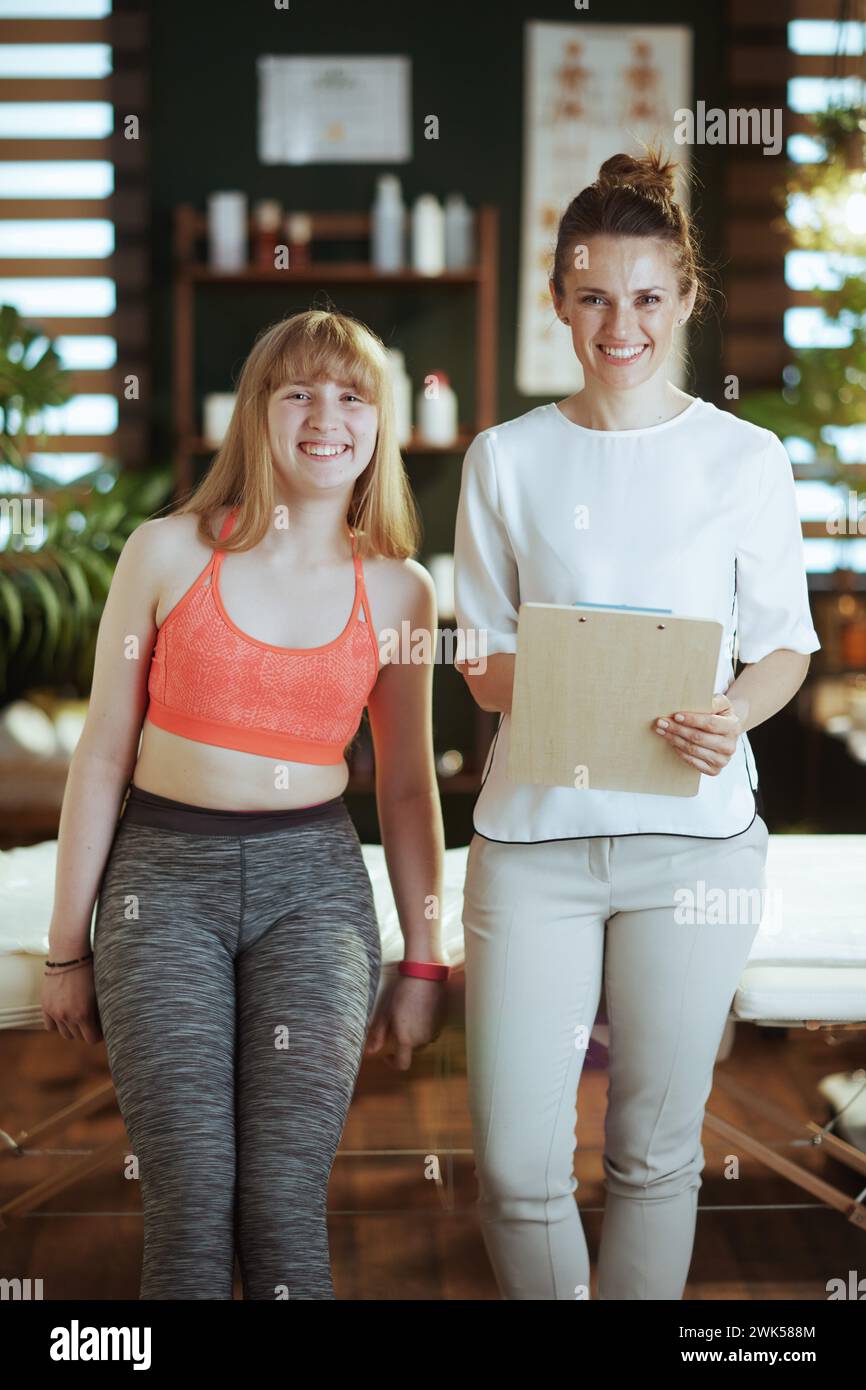 Healthcare time. happy female medical massage therapist in massage cabinet with clipboard and ...