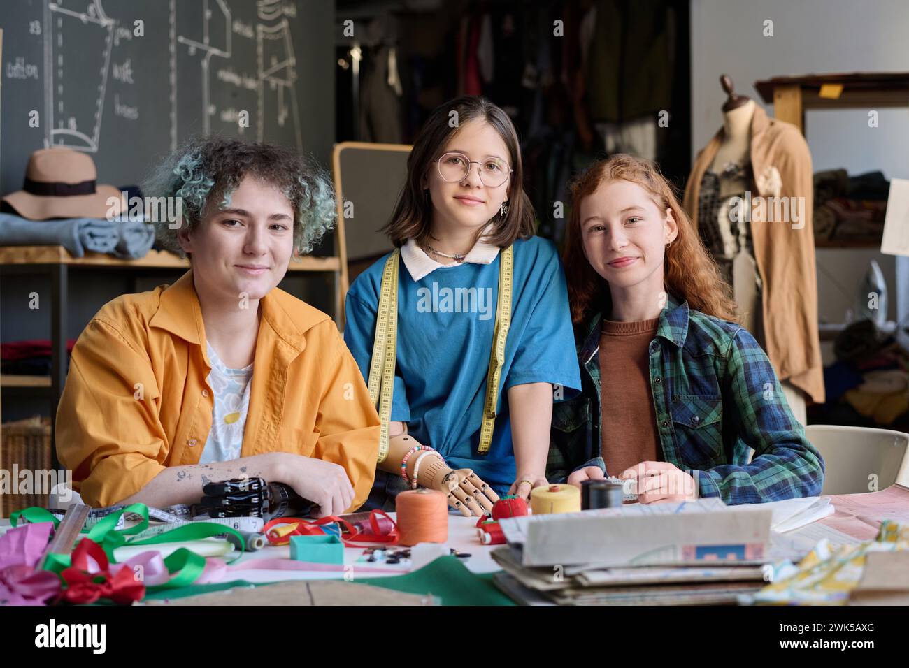 Inclusive group of three girls smiling at camera enjoying tailoring ...