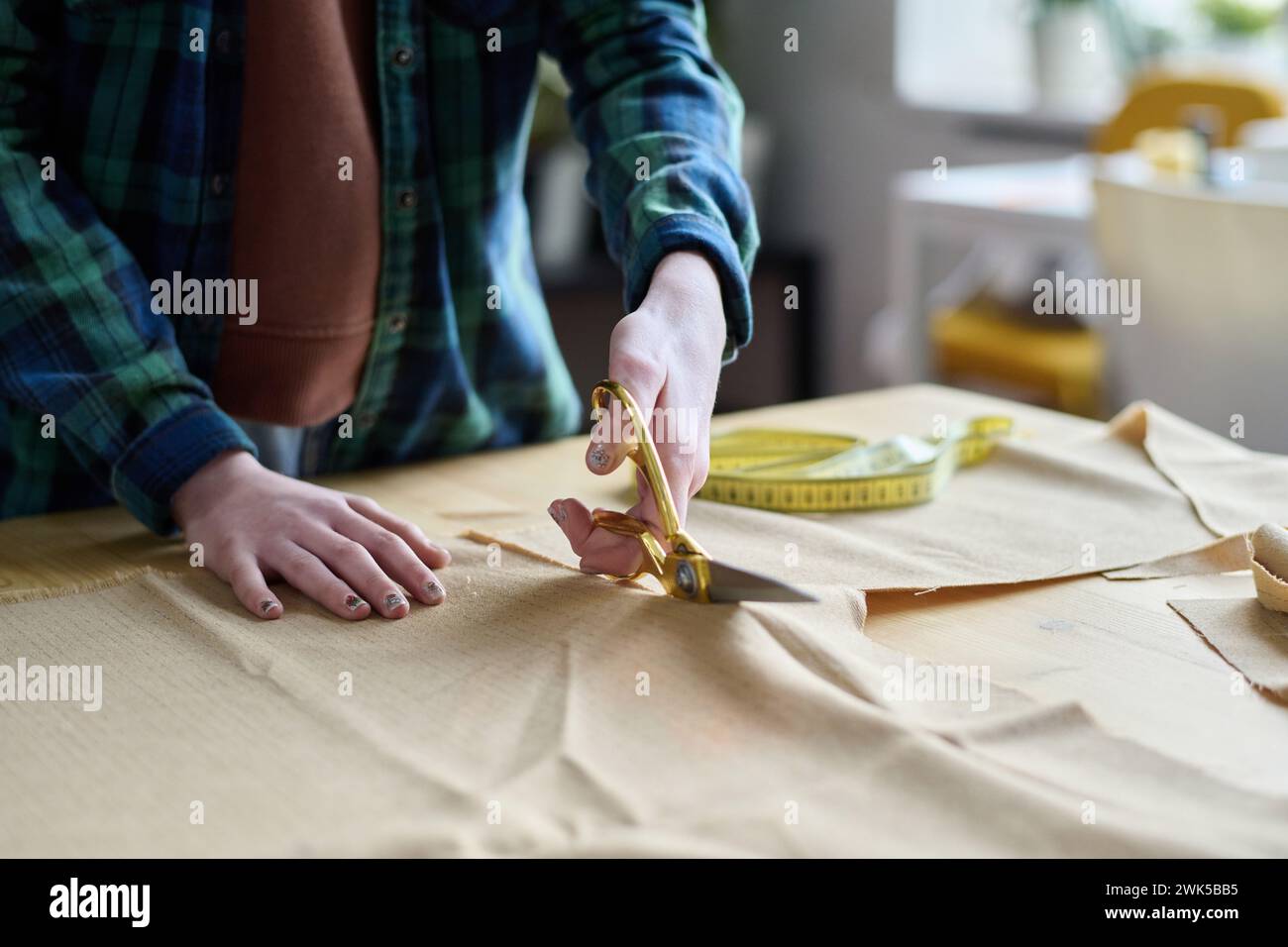Close up of teenage girl carefully cutting fabric with gold scissors ...