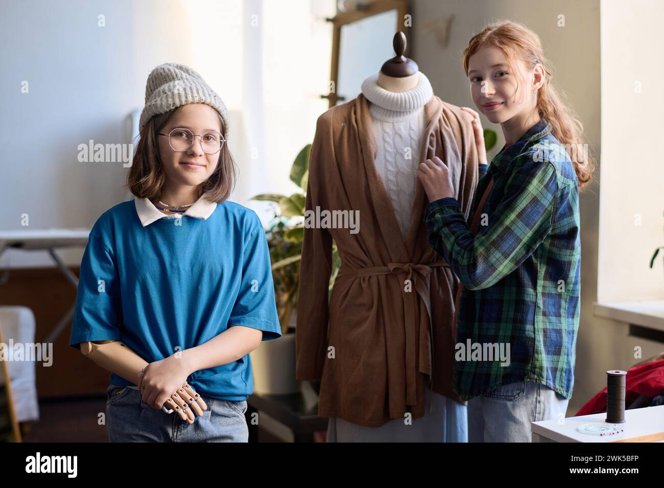 Waist up portrait of two teenage girls designing outfits on mannequin ...