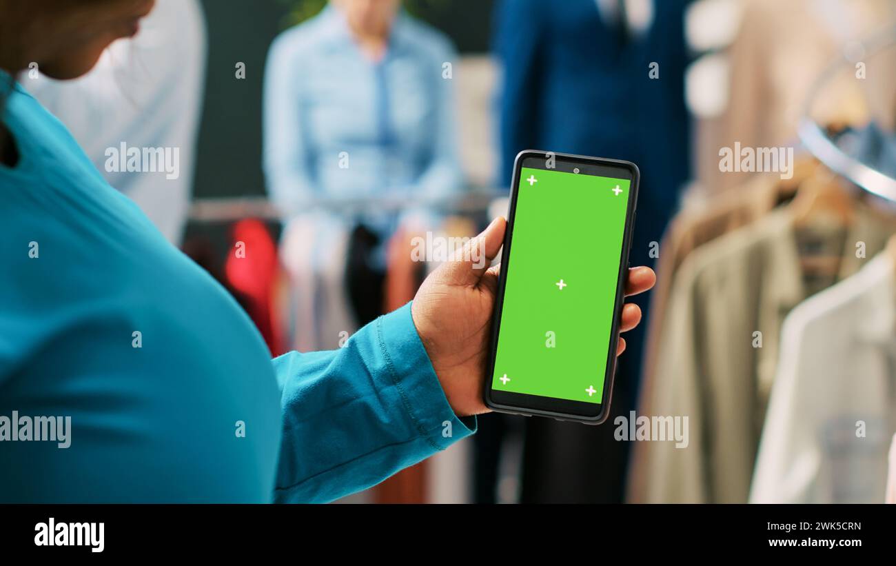 African american client holding smartphone with green screen template ...