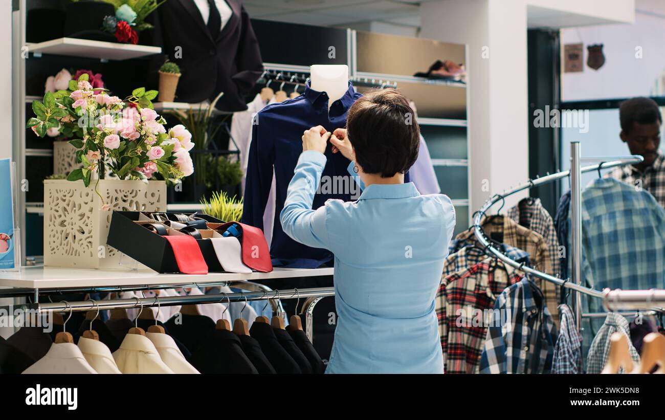 Employee working at boutique opening, putting formal wear on mannequin ...