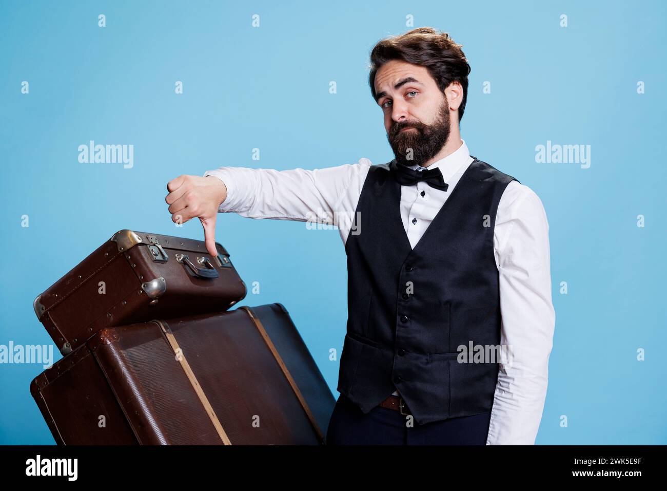 While showing thumbs down and donning formal outfit, hotel employee ...