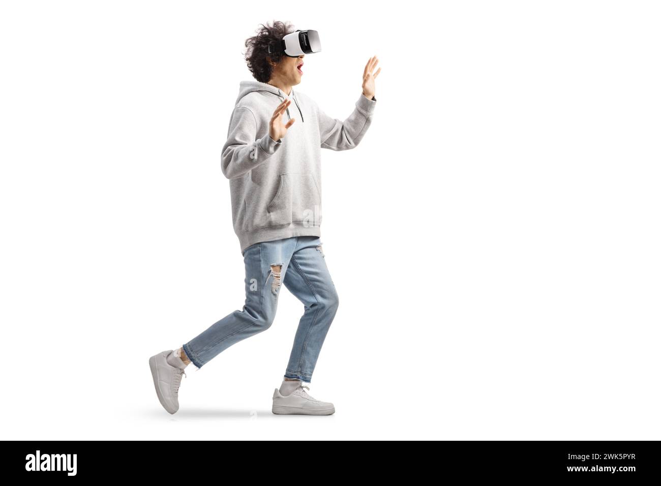 Young casual man with a VR headset walking and touching with hands ...