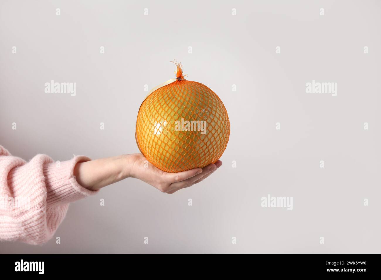 Female hand holding sweet pomelo in net on white background Stock Photo ...