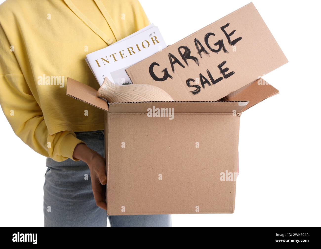 Woman holding box of unwanted stuff and cardboard with text GARAGE SALE ...