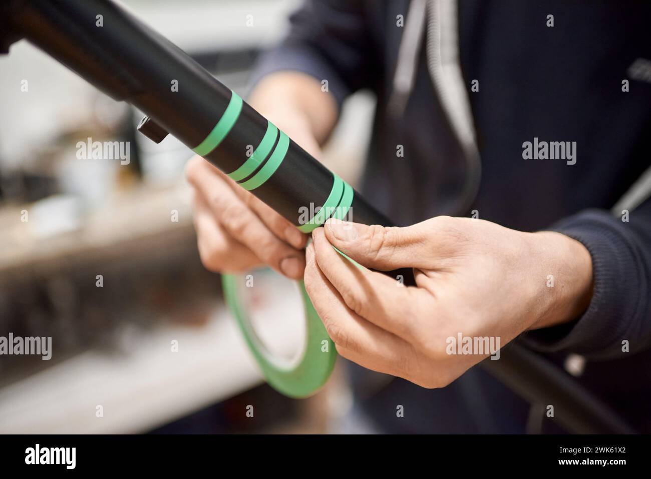 Unrecognizable person preparing a bicycle frame with masking tape for a ...