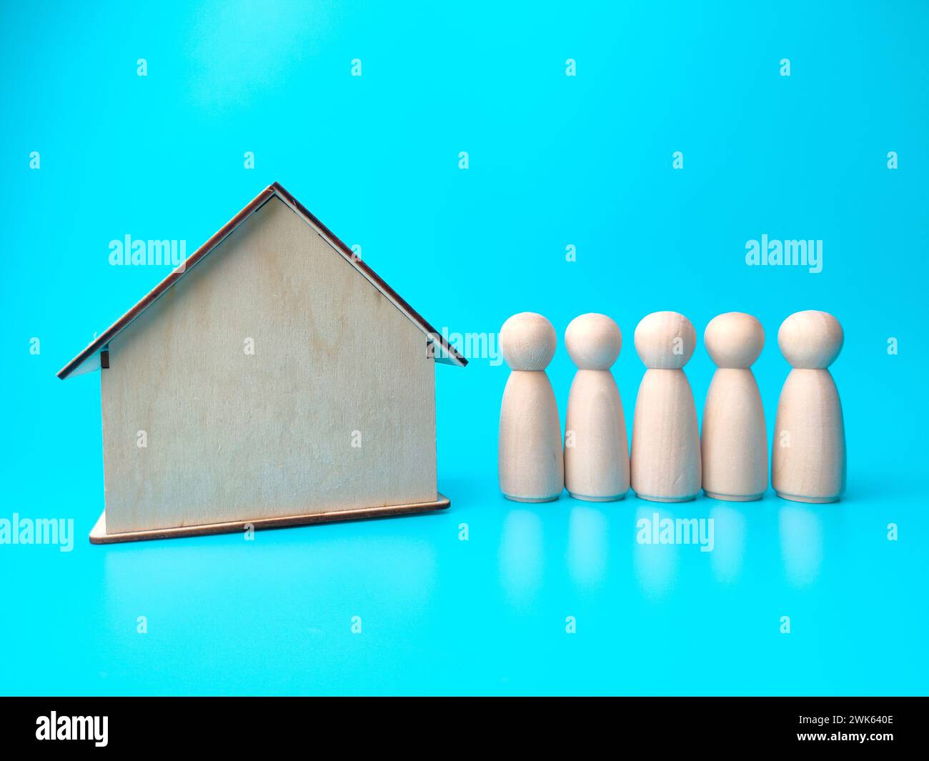 Wooden people figures and wooden house on blue background. Real estate ...
